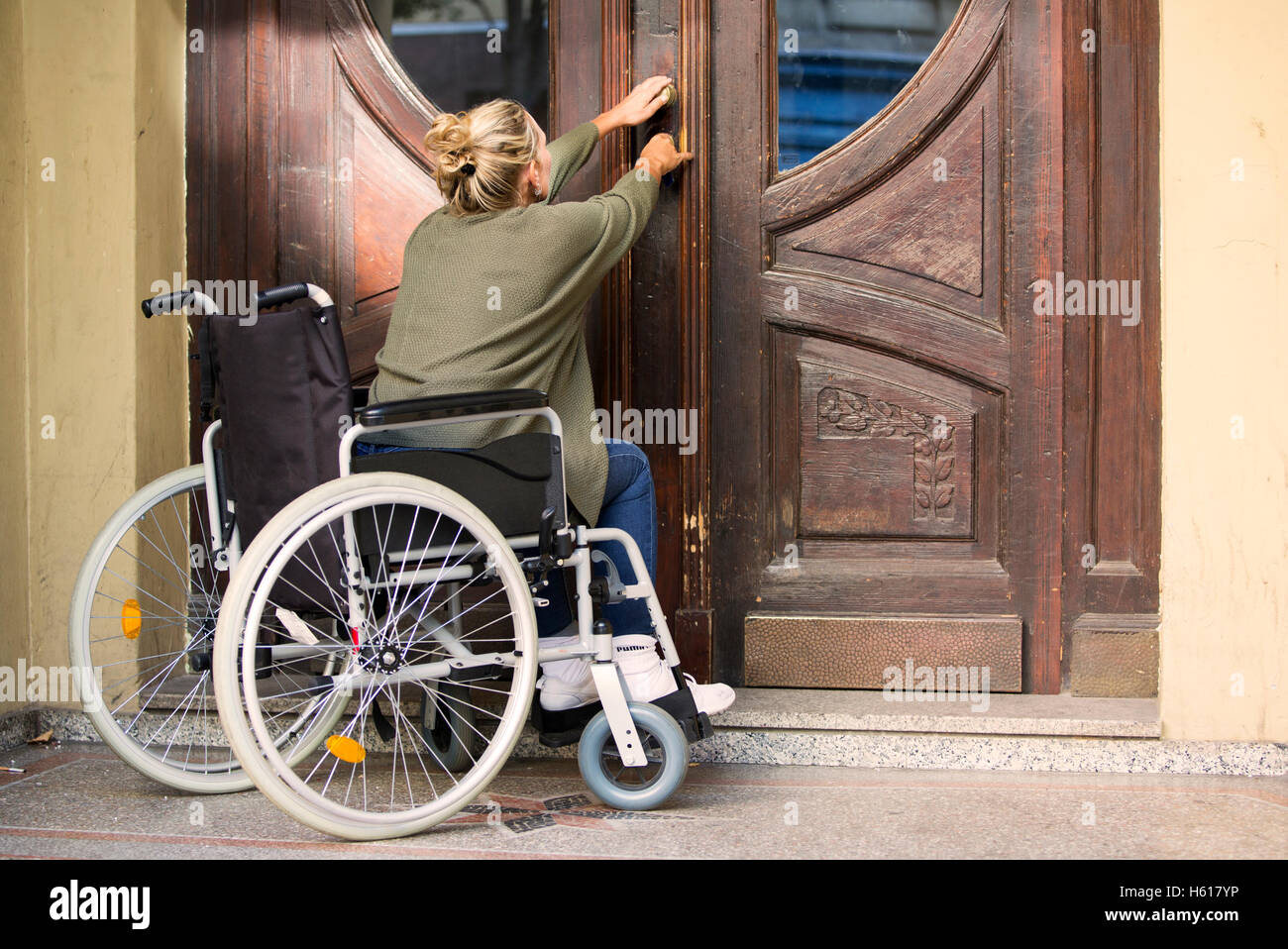 woman in wheelchair in front of entrance door trying to get in Stock ...