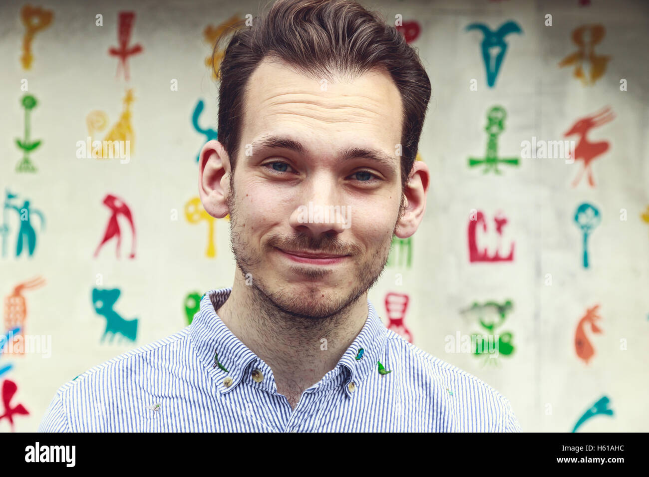Portrait of an accepting young man standing against a colourful funky ...