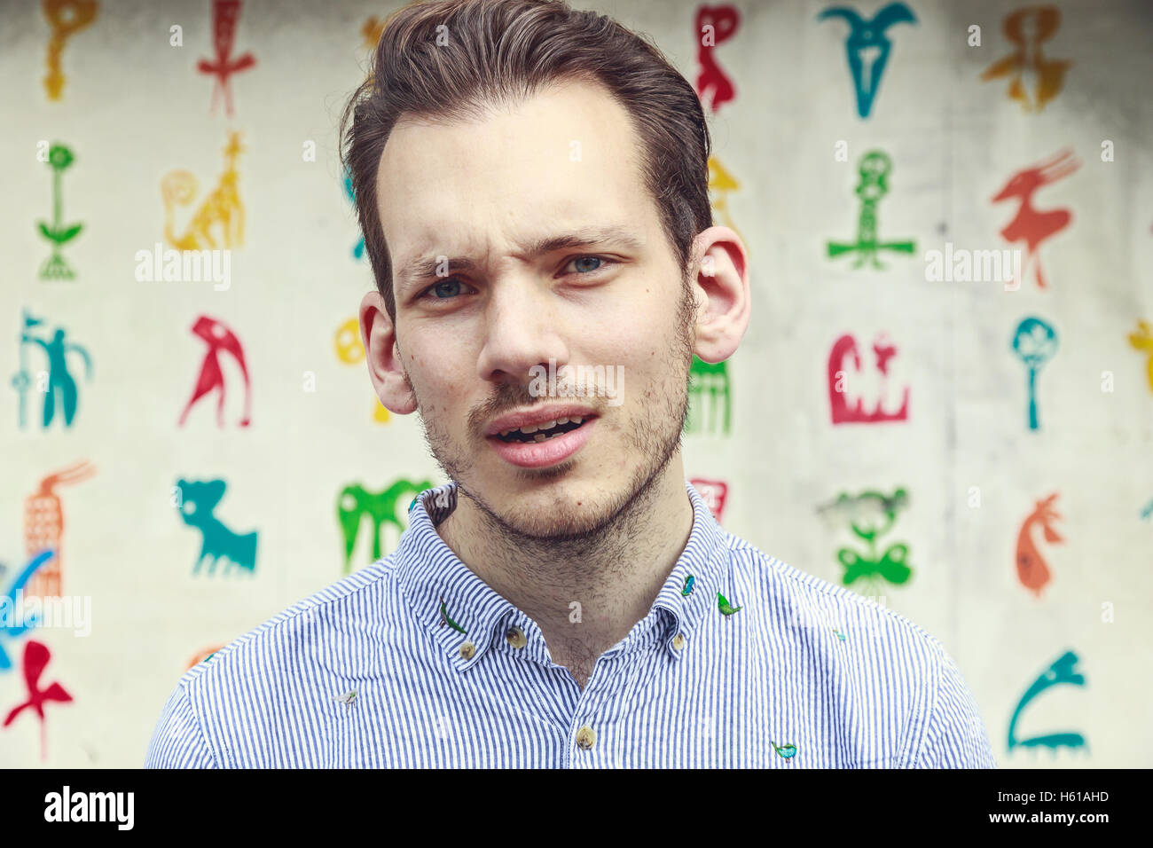Portrait of a aggravated young man standing against a colourful funky ...