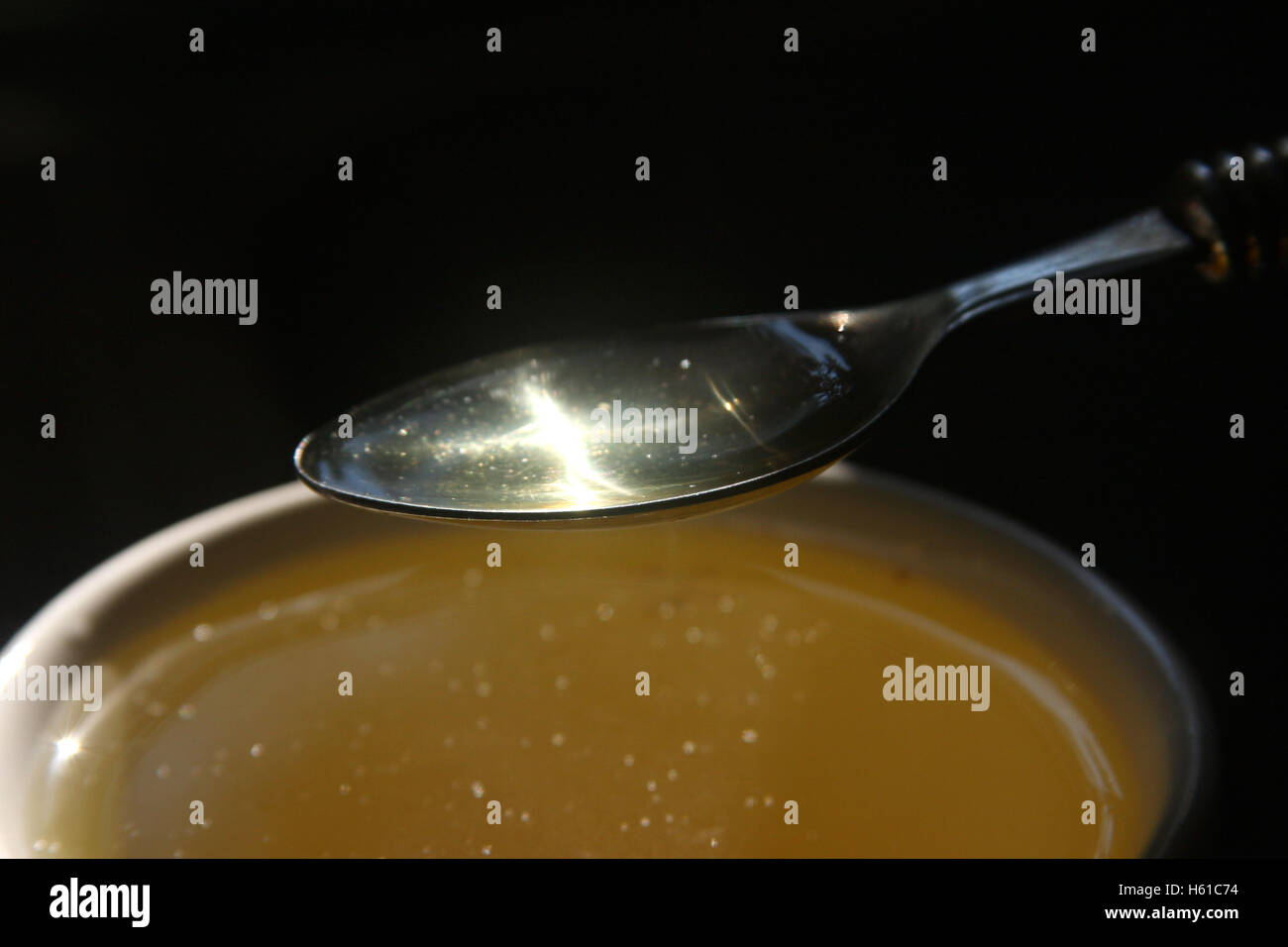 Teaspoon filled with honey poured into cup of tea Stock Photo - Alamy