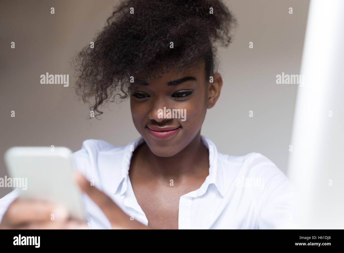 African female freelancer with Afro hairstyle, dressed casually, using ...