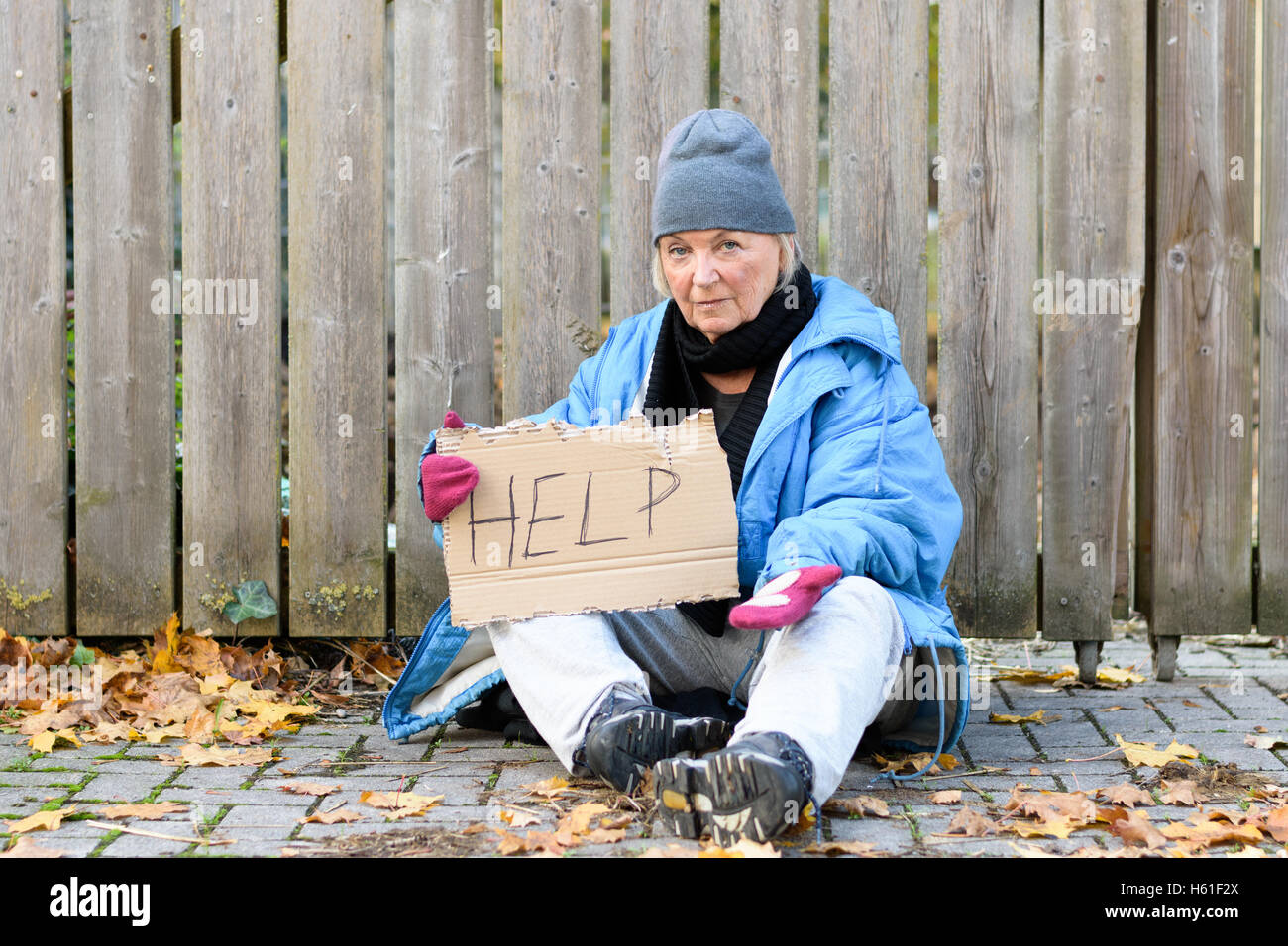 Elderly homeless woman begging on the street in cold autumn weather ...
