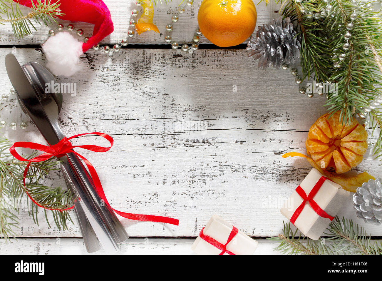 Christmas tree branch, ornaments and cutlery on a white wooden table ...