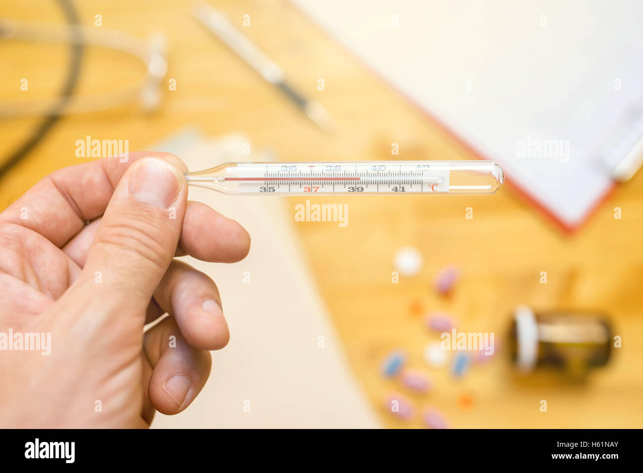 Hand with medical thermometer measuring human body temperature, close ...