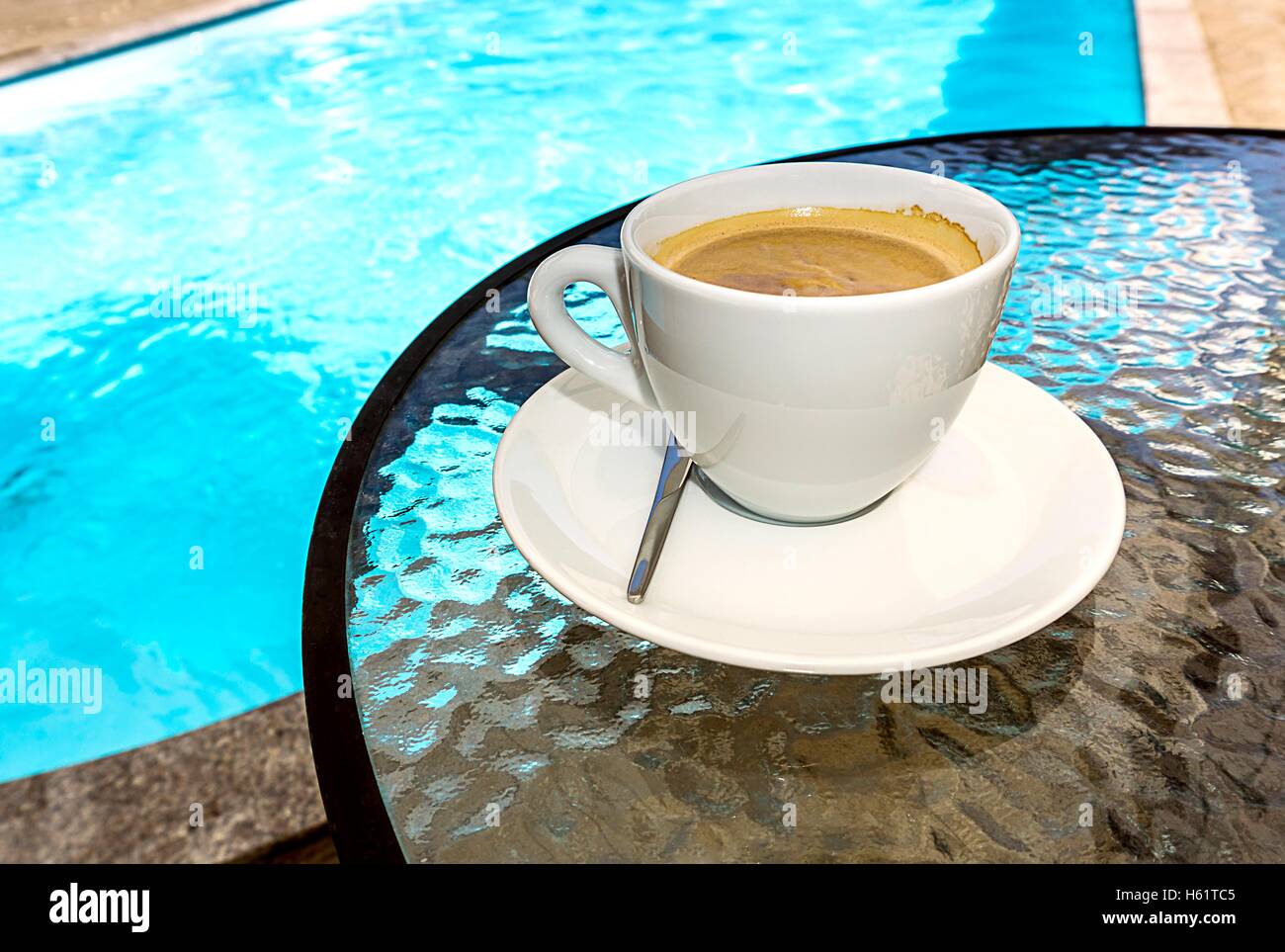 Cup of coffee on glassy table by the swimming pool Stock Photo - Alamy