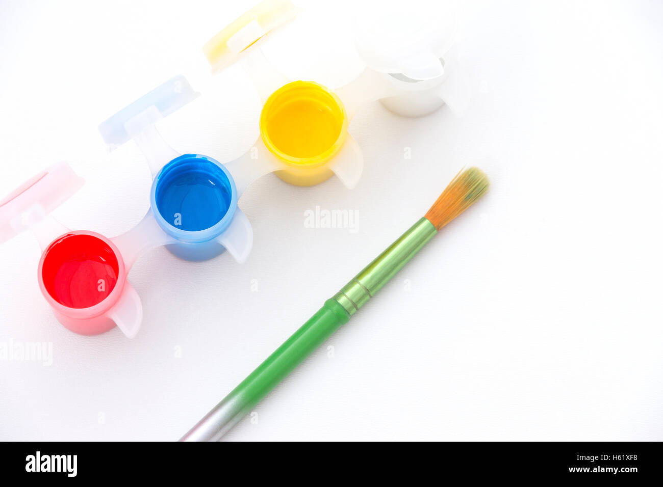 Paint pots with vibrant red, yellow, blue and white paint, alongside a ...