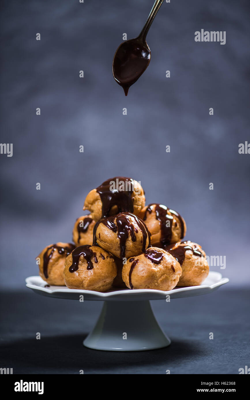Topping profiterole tower with melted dark chocolate Stock Photo - Alamy