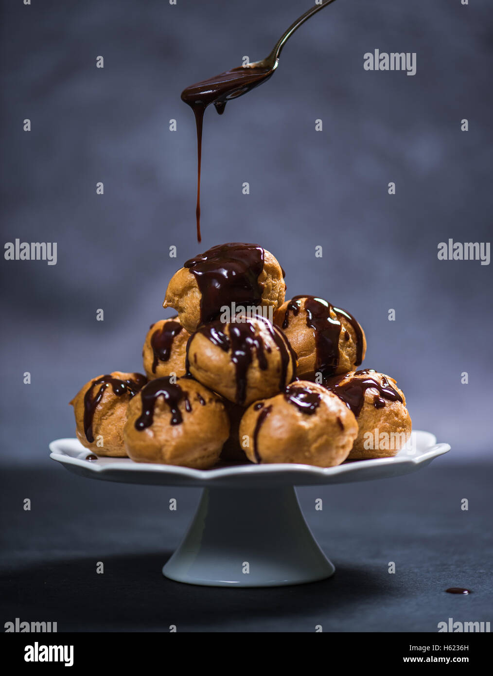 Topping profiterole tower with melted dark chocolate Stock Photo - Alamy