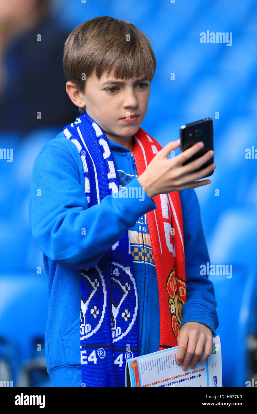 A young fan looks at his phone prior to the Premier League match at ...