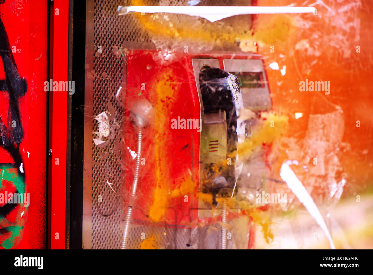 Demolished and vandalized public phone booth on street with graffiti ...