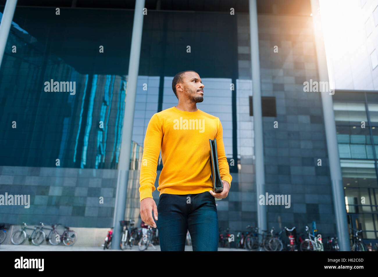 Young man with file wearing yellow pullover Stock Photo - Alamy