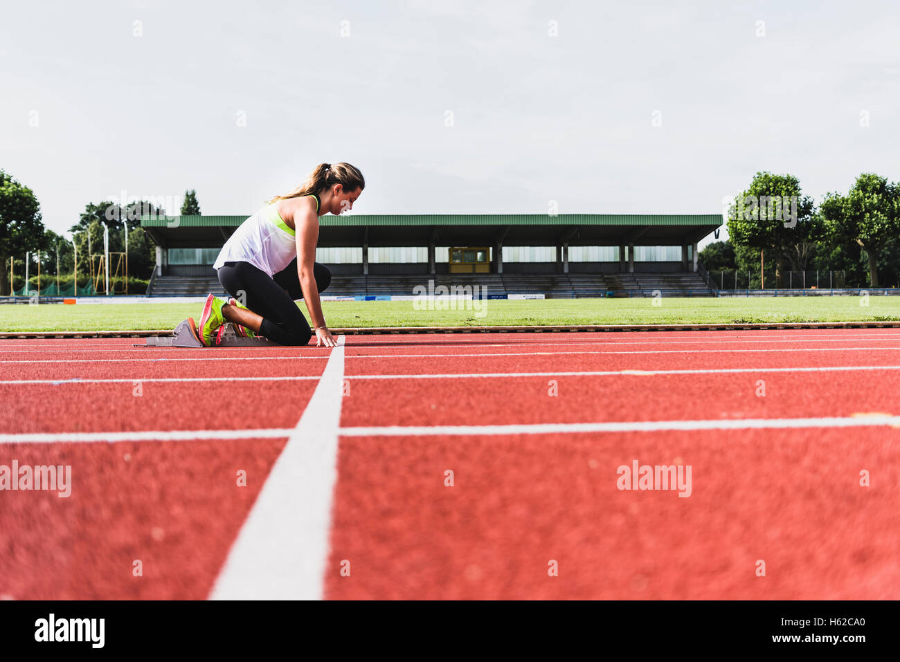 Young woman on tartan track in starting position Stock Photo - Alamy