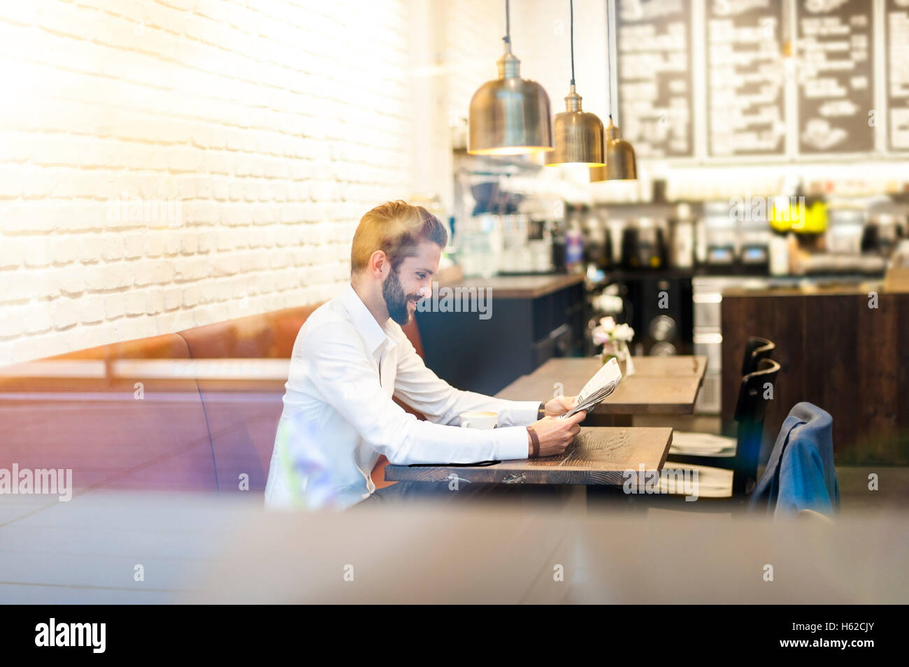 Businessman sitting in a cafe reading newspaper Stock Photo - Alamy