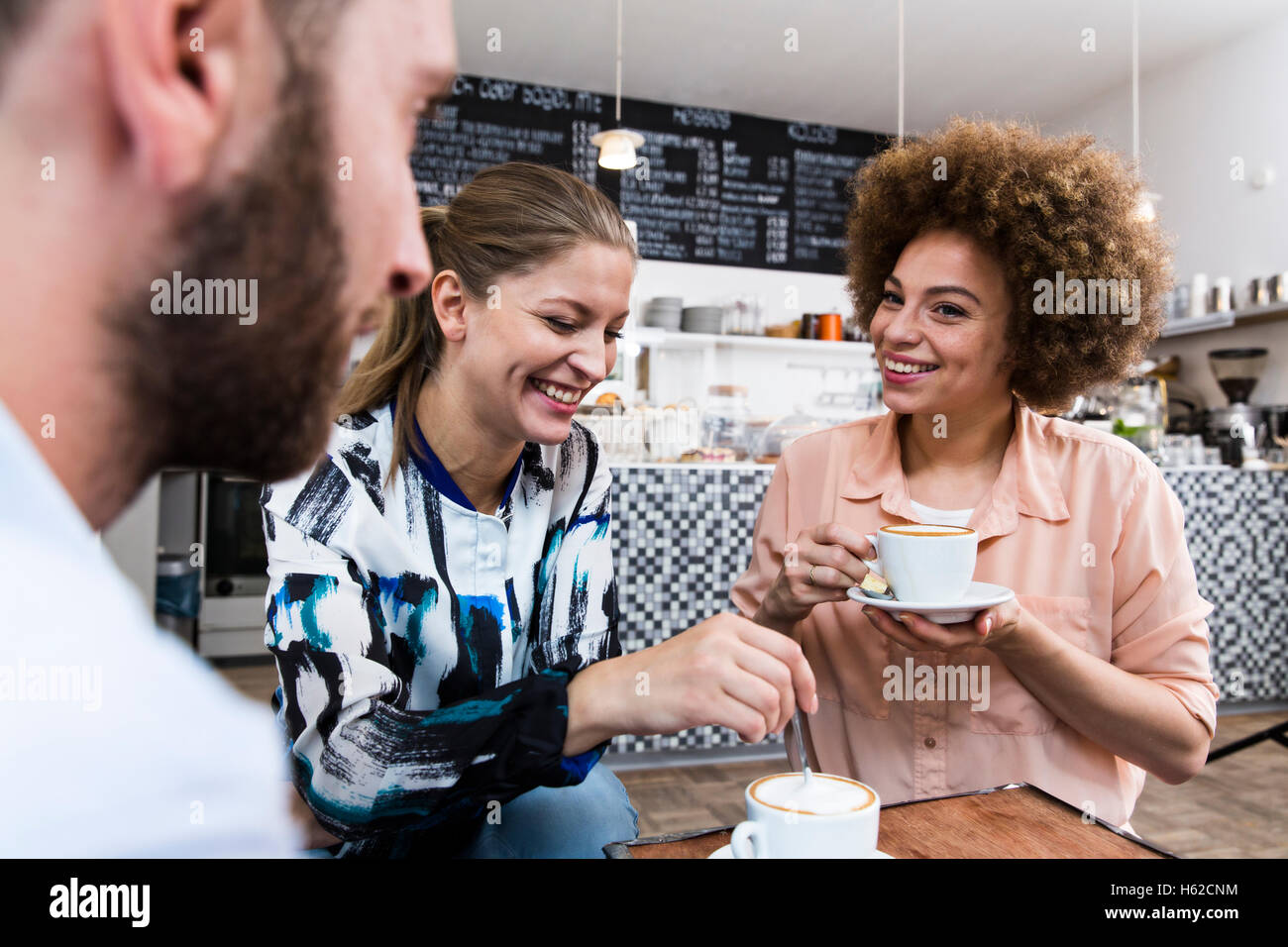 Three friends meeting in a cafe Stock Photo - Alamy