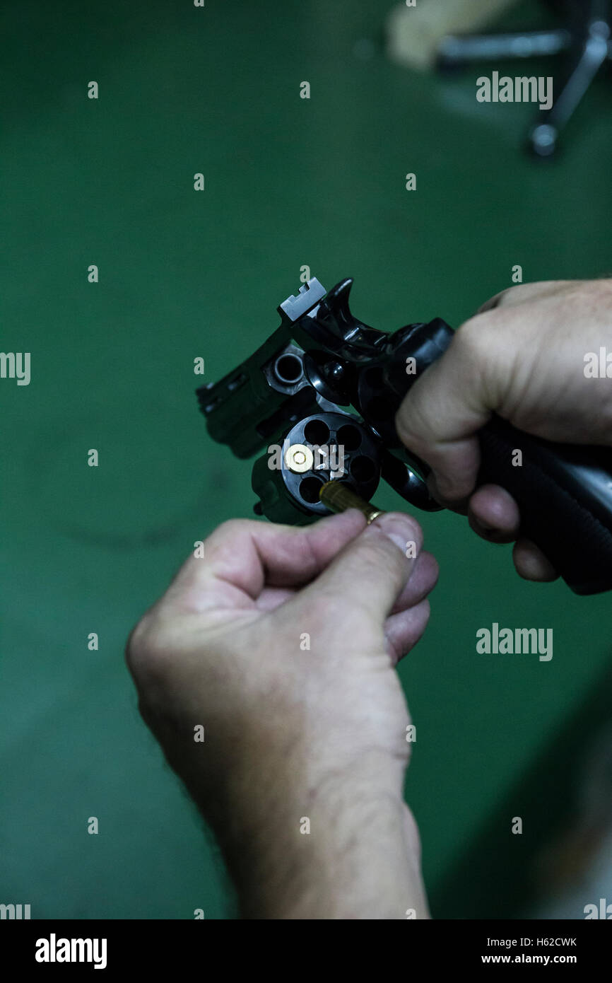 Hands of a man reloading a revolver with bullets Stock Photo - Alamy