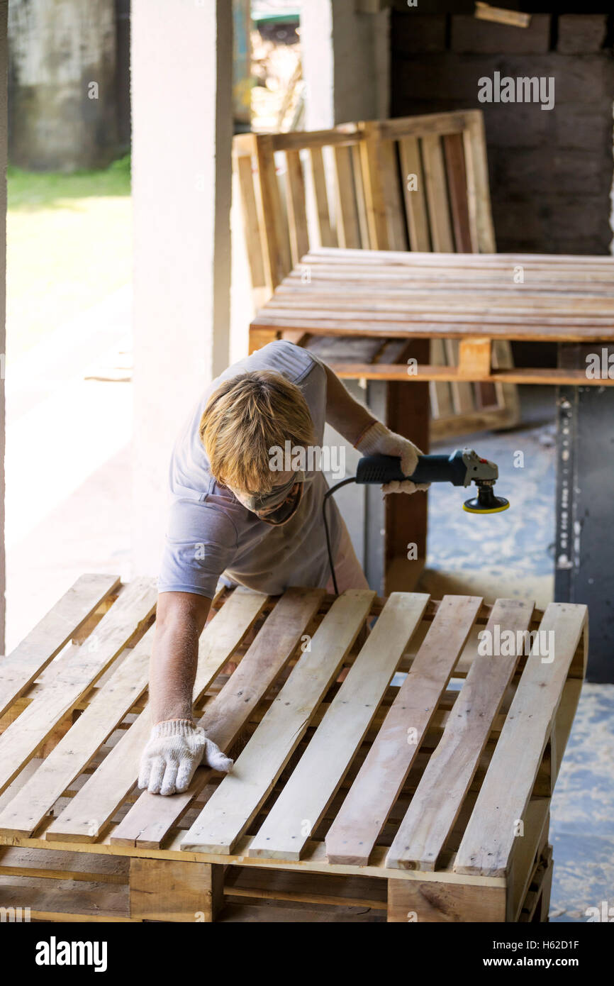 Man sanding pallet with a random orbital sander Stock Photo - Alamy
