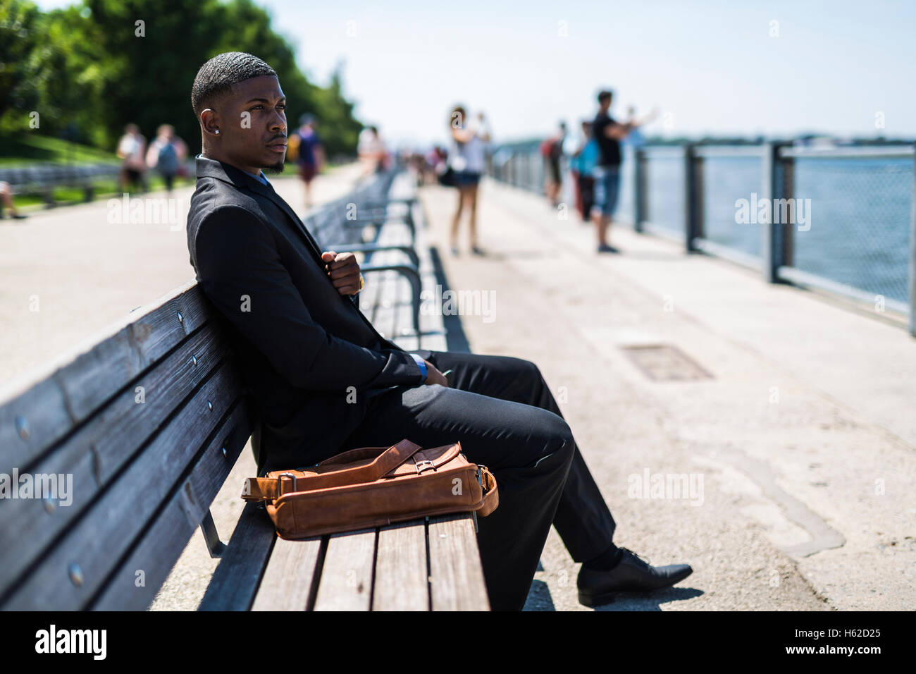 Businessman sitting on bench looking at distance Stock Photo - Alamy