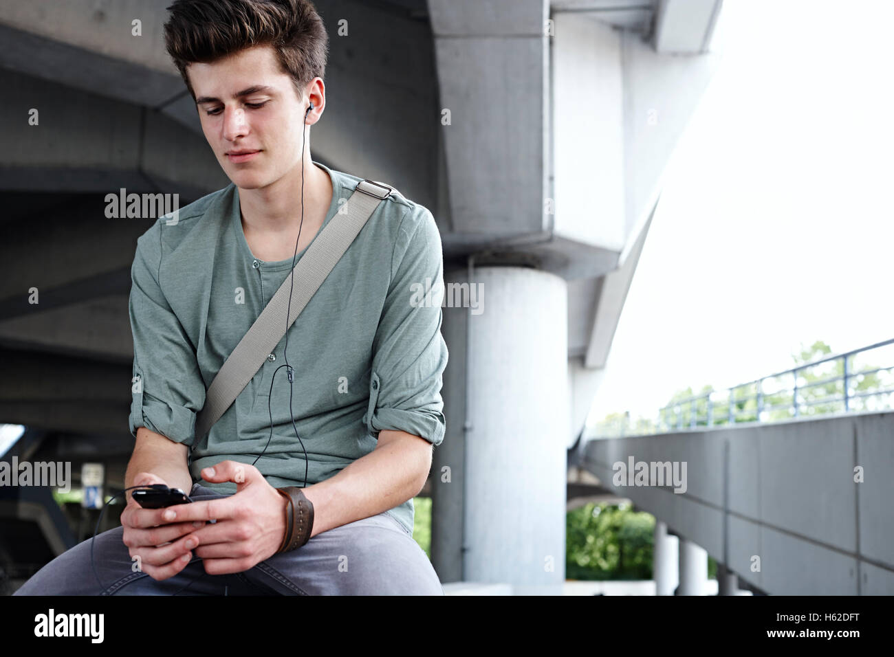 Teenage boy with cell phone and earbuds outdoors Stock Photo - Alamy