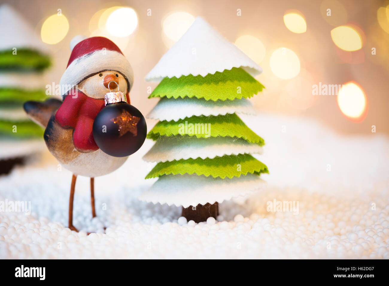 Robin with Christmas ball in a forest, Christmas lights in a background ...