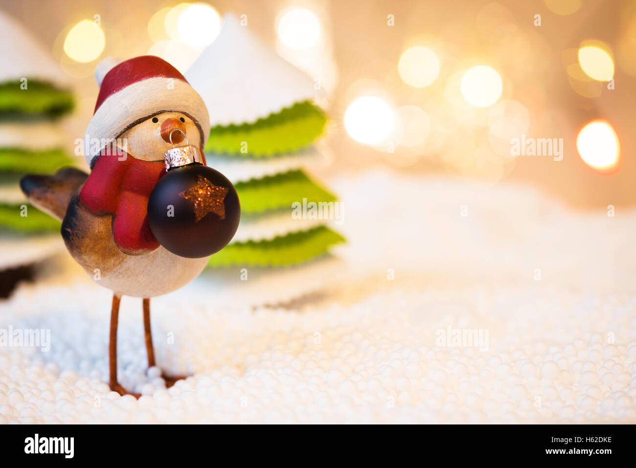 Robin with Christmas ball in a forest, Christmas lights in a background ...