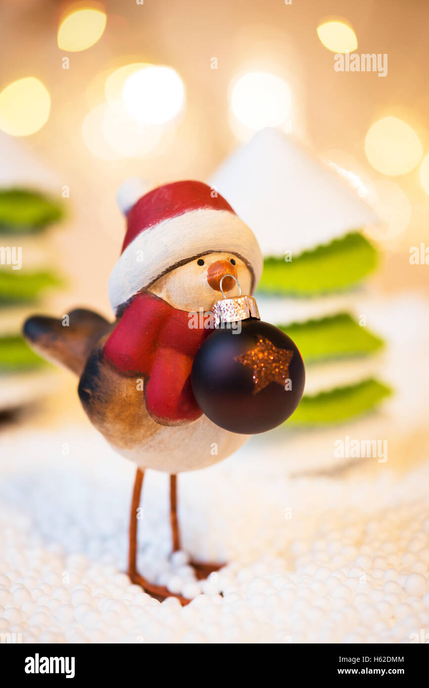 Robin with Christmas ball in a forest, Christmas lights in a background ...