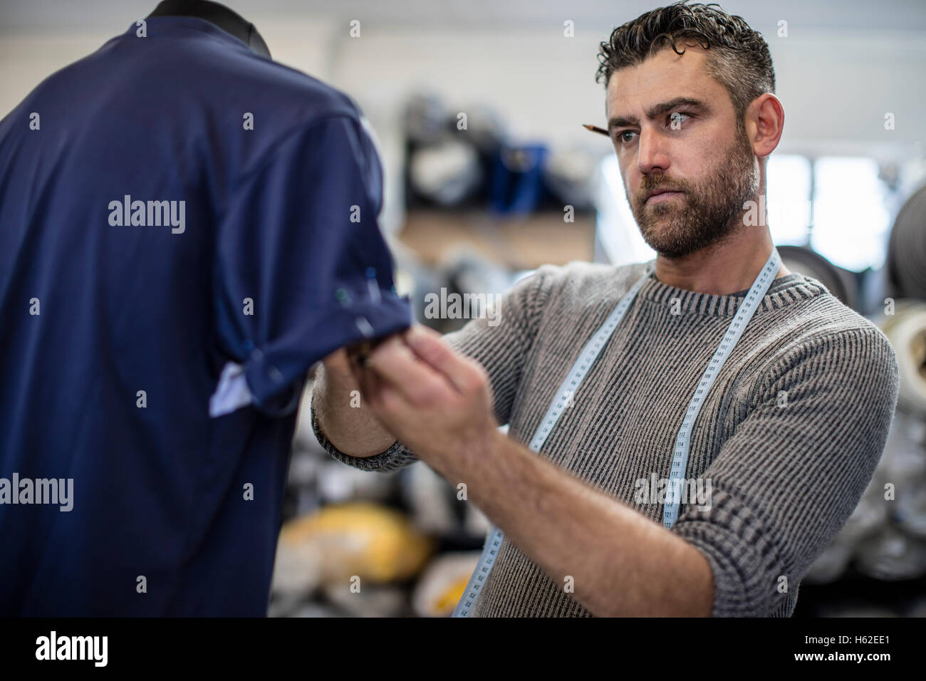 Tailor pinning sleeves of sports shirt on mannequin in workshop Stock ...
