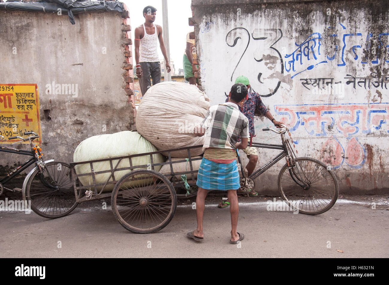 Three man lifting parcels on Cycle rickshaw near railway station ...