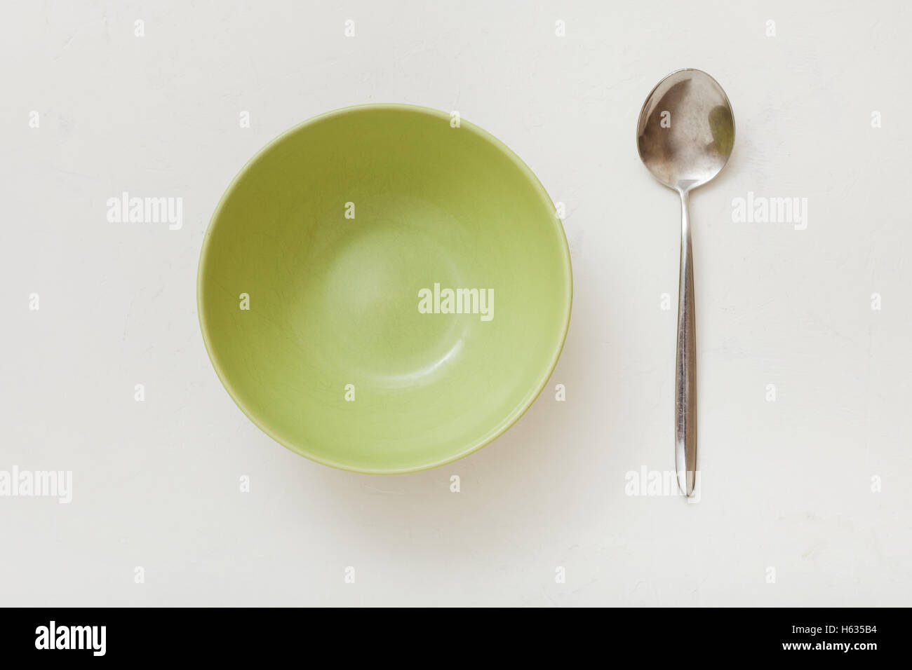 top view of green bowl and spoon on white plastering plate Stock Photo ...