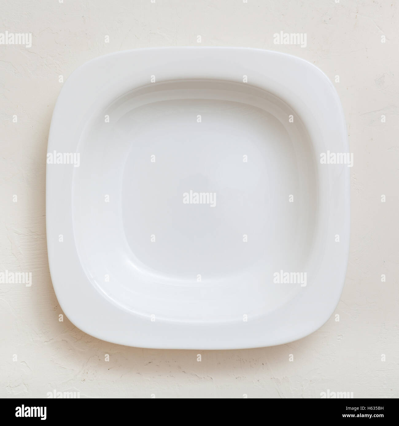 top view of square white deep plate on plastering surface Stock Photo ...
