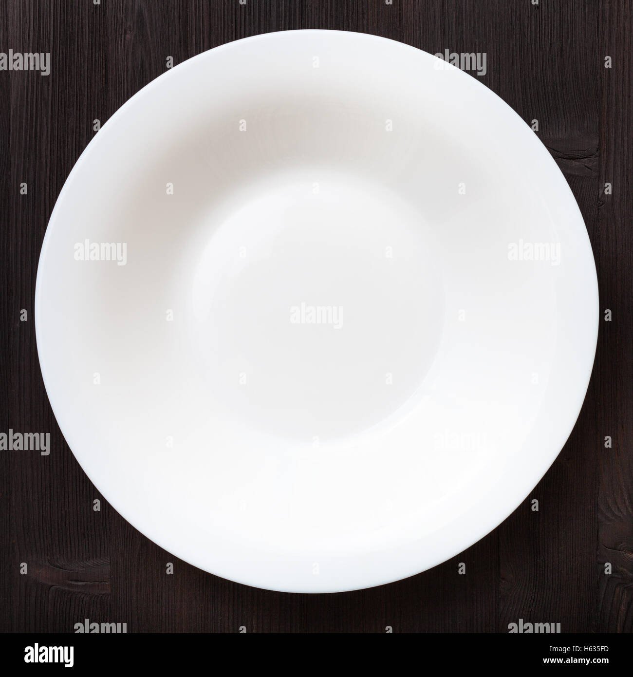 above view of one white deep plate on dark brown table Stock Photo - Alamy