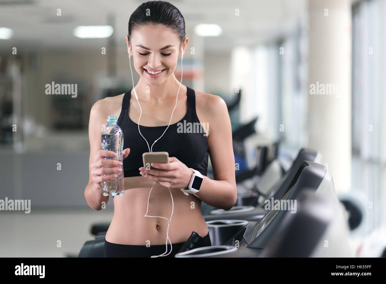 Athletic girl using smartphone in a gym Stock Photo - Alamy