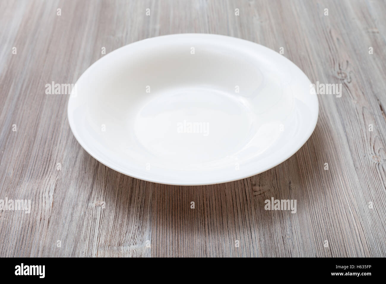 one white deep plate on gray brown board Stock Photo - Alamy