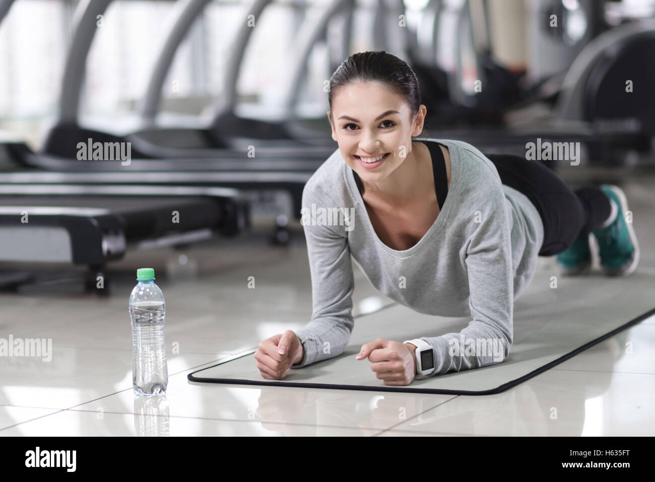 Smiling woman doing plank in a gym Stock Photo - Alamy