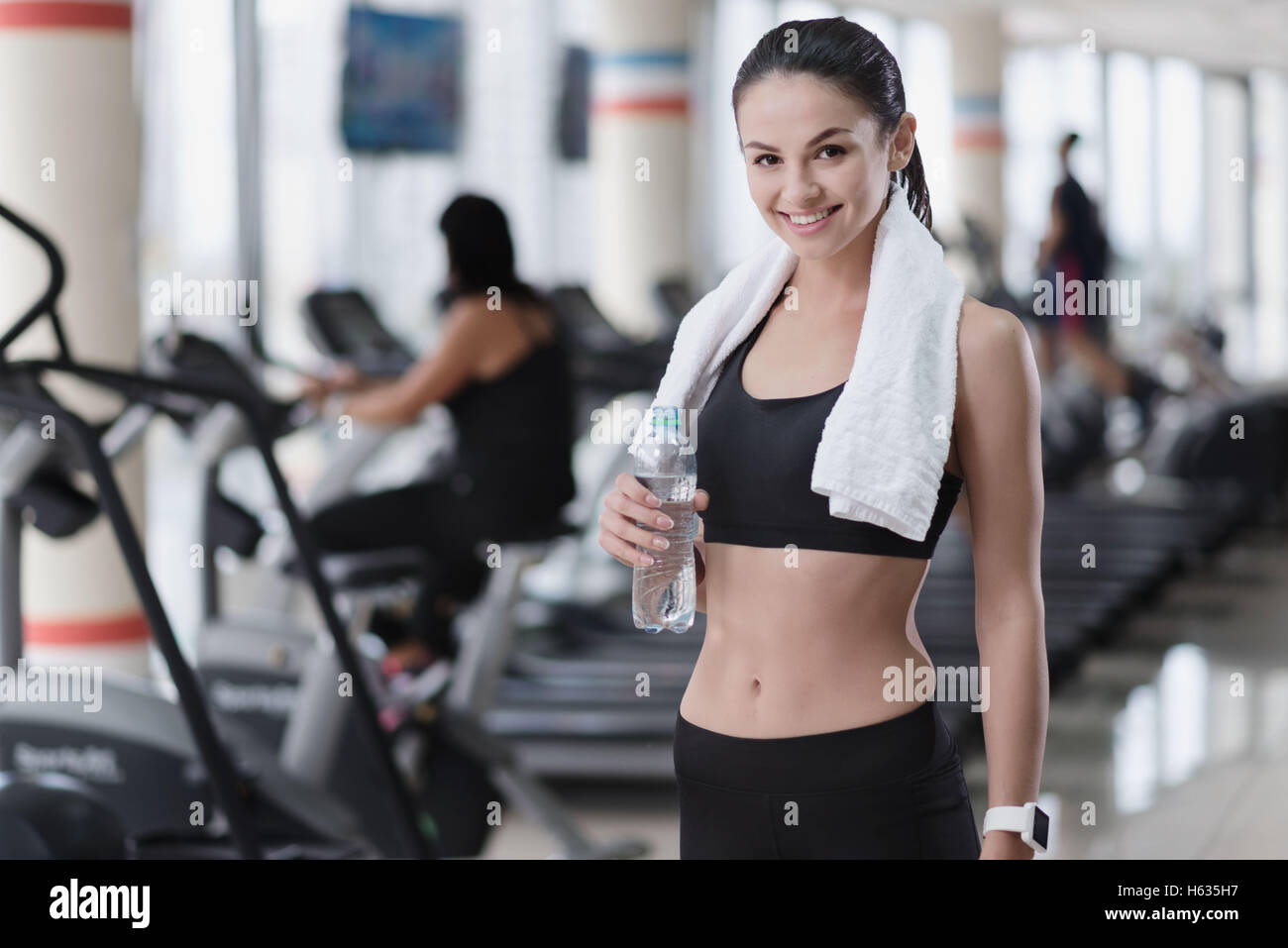 Smiling girl posing with a towel in gym Stock Photo - Alamy