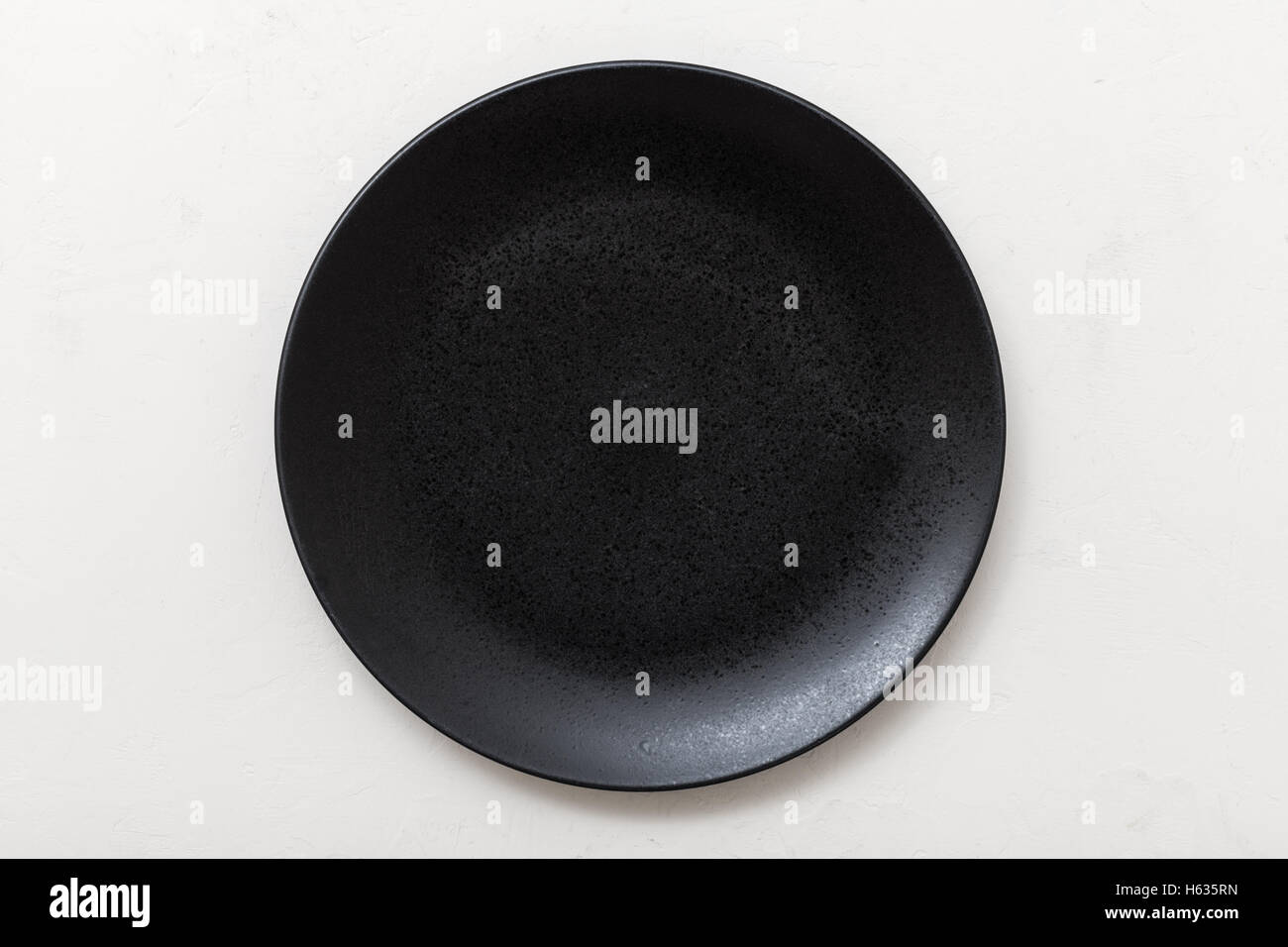 above view of one black plate on white plastering board Stock Photo - Alamy