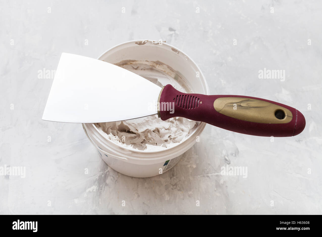 metal spatula with plastic handle on tube with putty on the concrete ...
