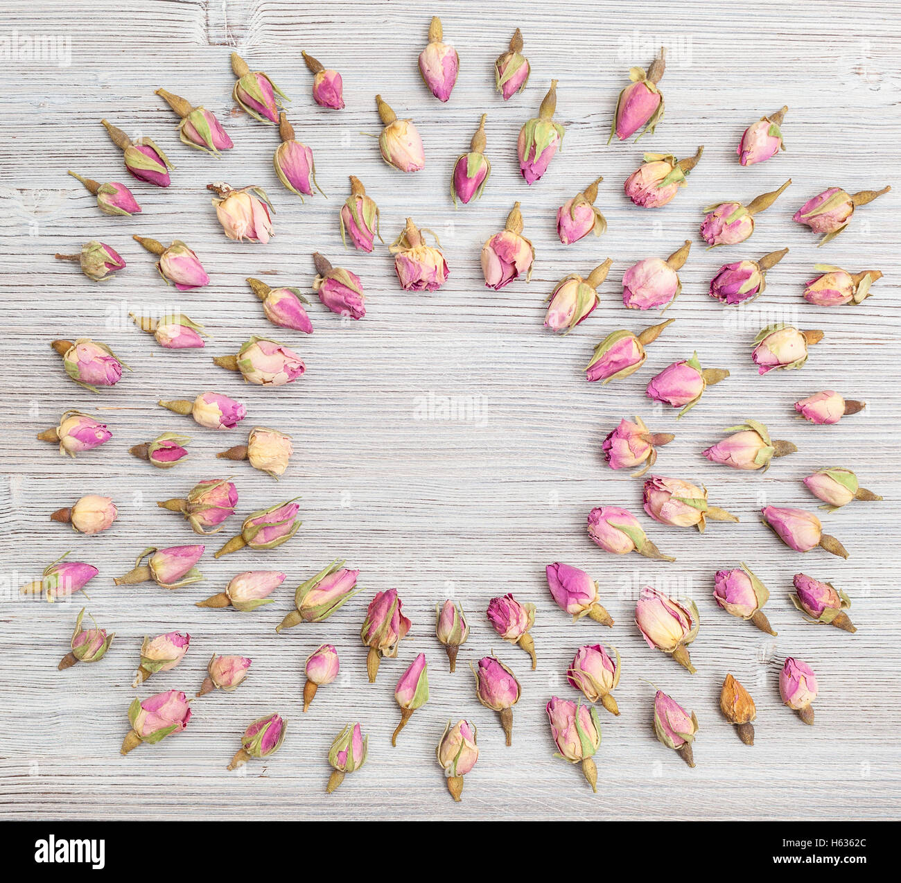round frame from many natural pink rose flower buds on wooden board ...