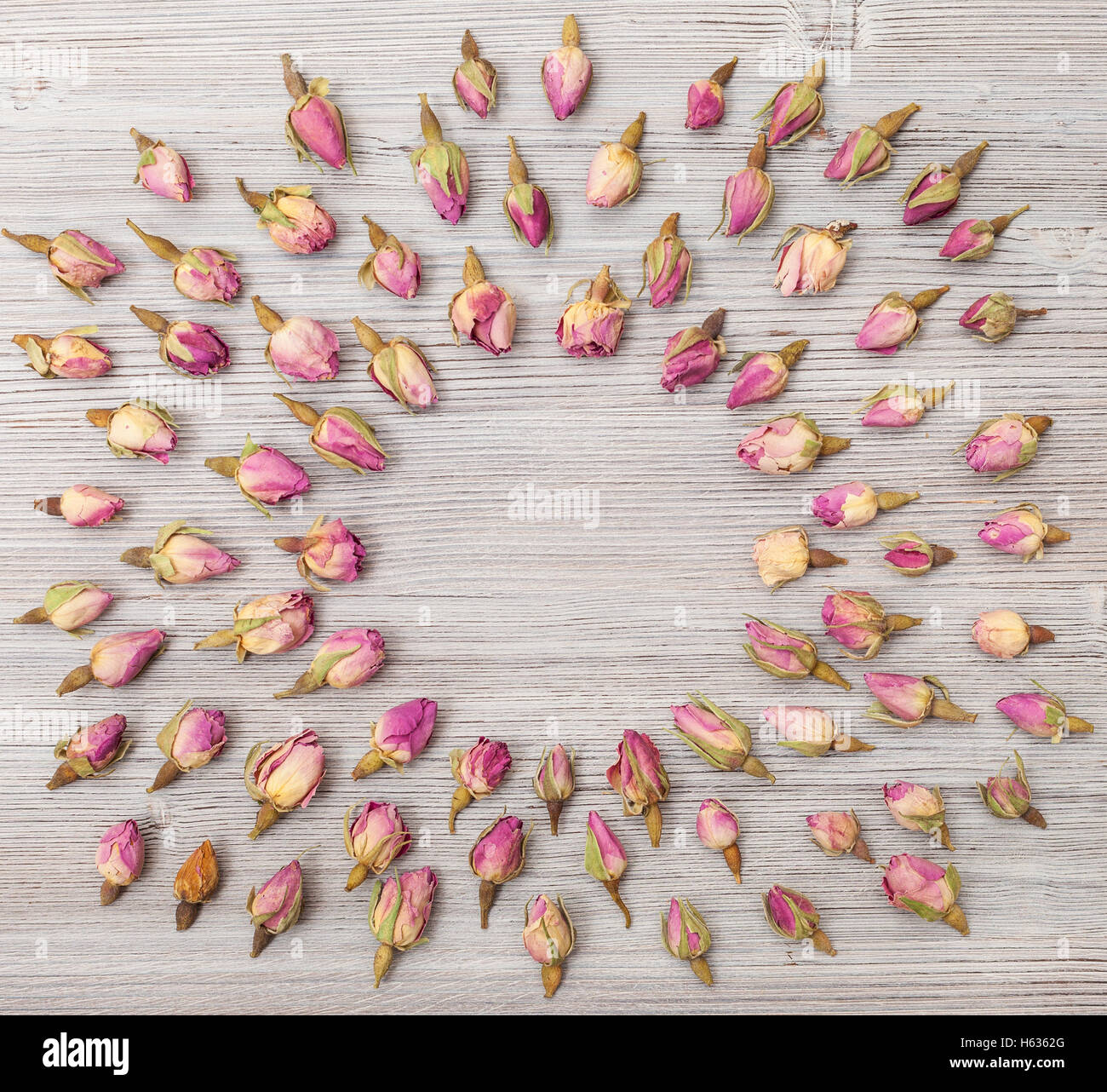 round frame from many natural pink rose flower buds on wooden plank ...