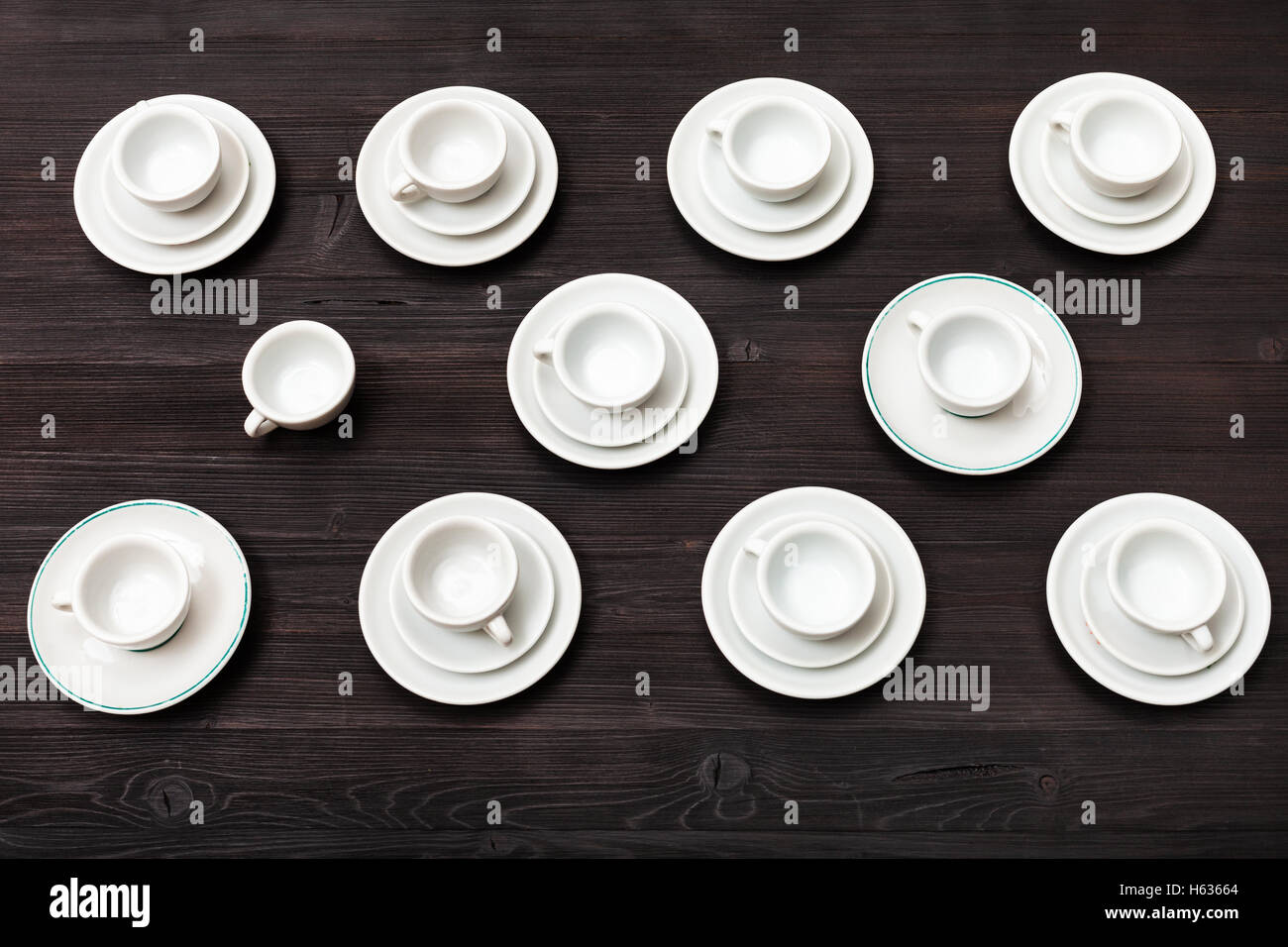 food concept - above view of many white cups and saucers on dark brown ...