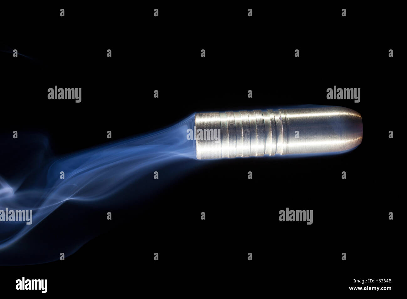 Copper colored bullet with blue smoke on a black background Stock Photo ...