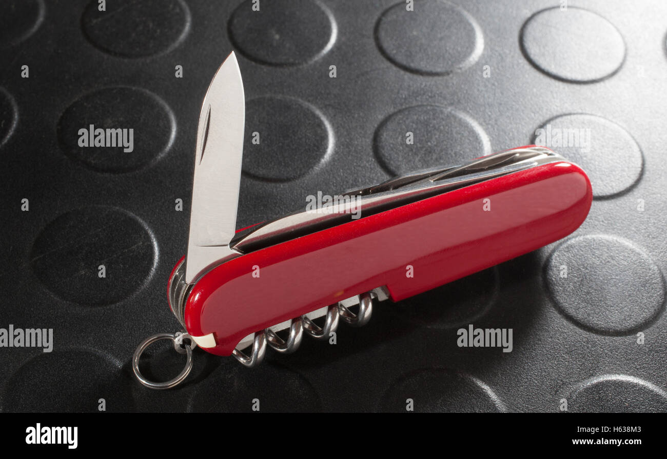 Red knife with one of the many blades out on a dark background Stock ...