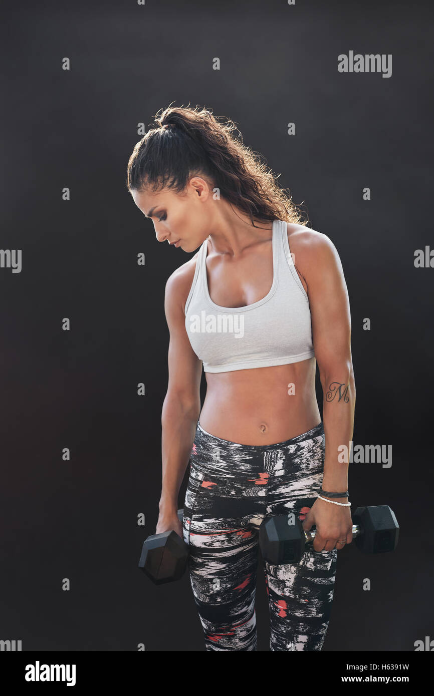 Shot of strong and muscular woman exercising with weights. Female ...