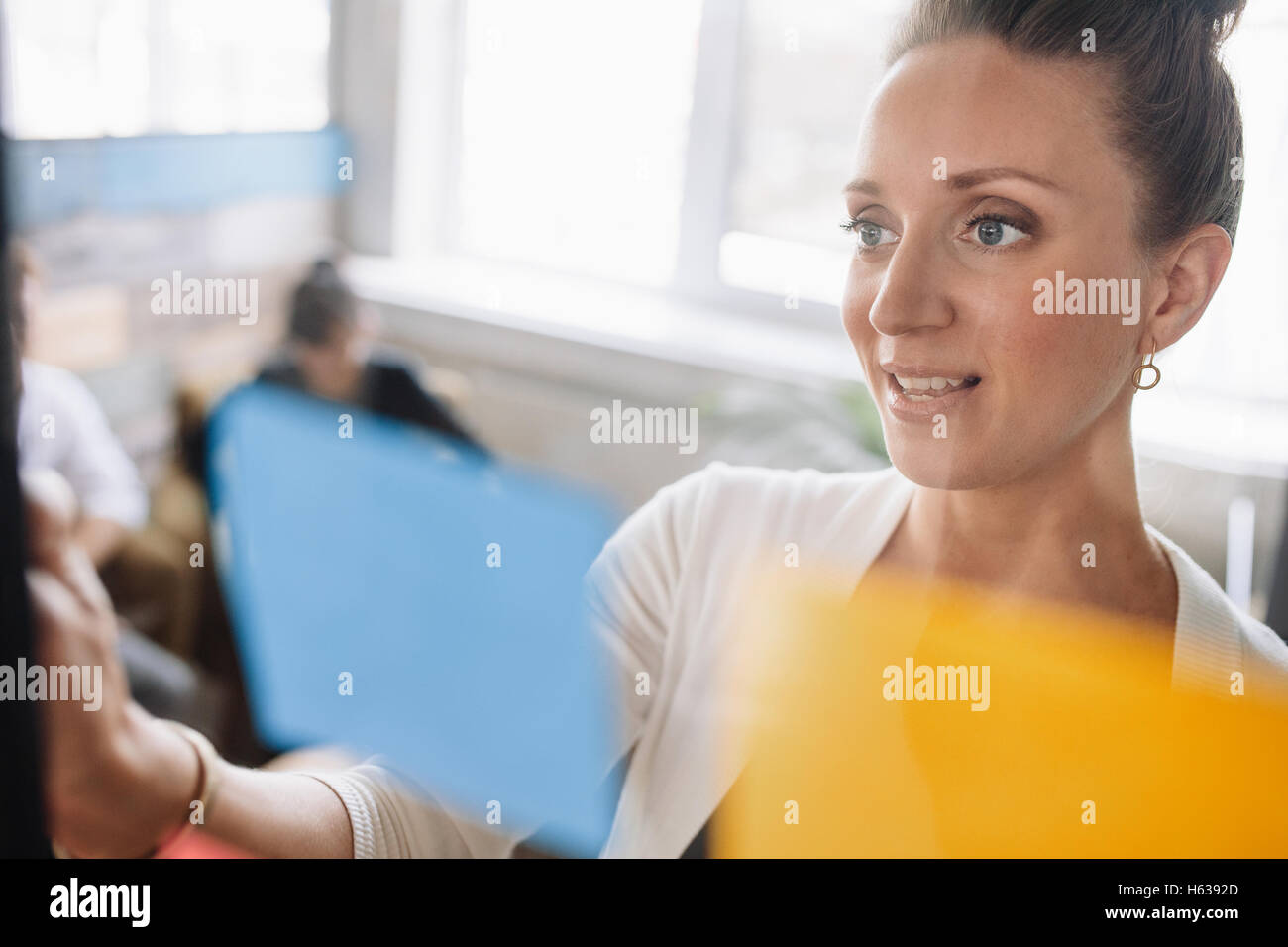 Young woman looking over a post it note wall and brainstorming ...