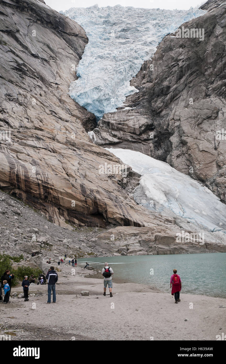 Tourists admiring the Briksdal Glacier by the meltwater lagoon ...