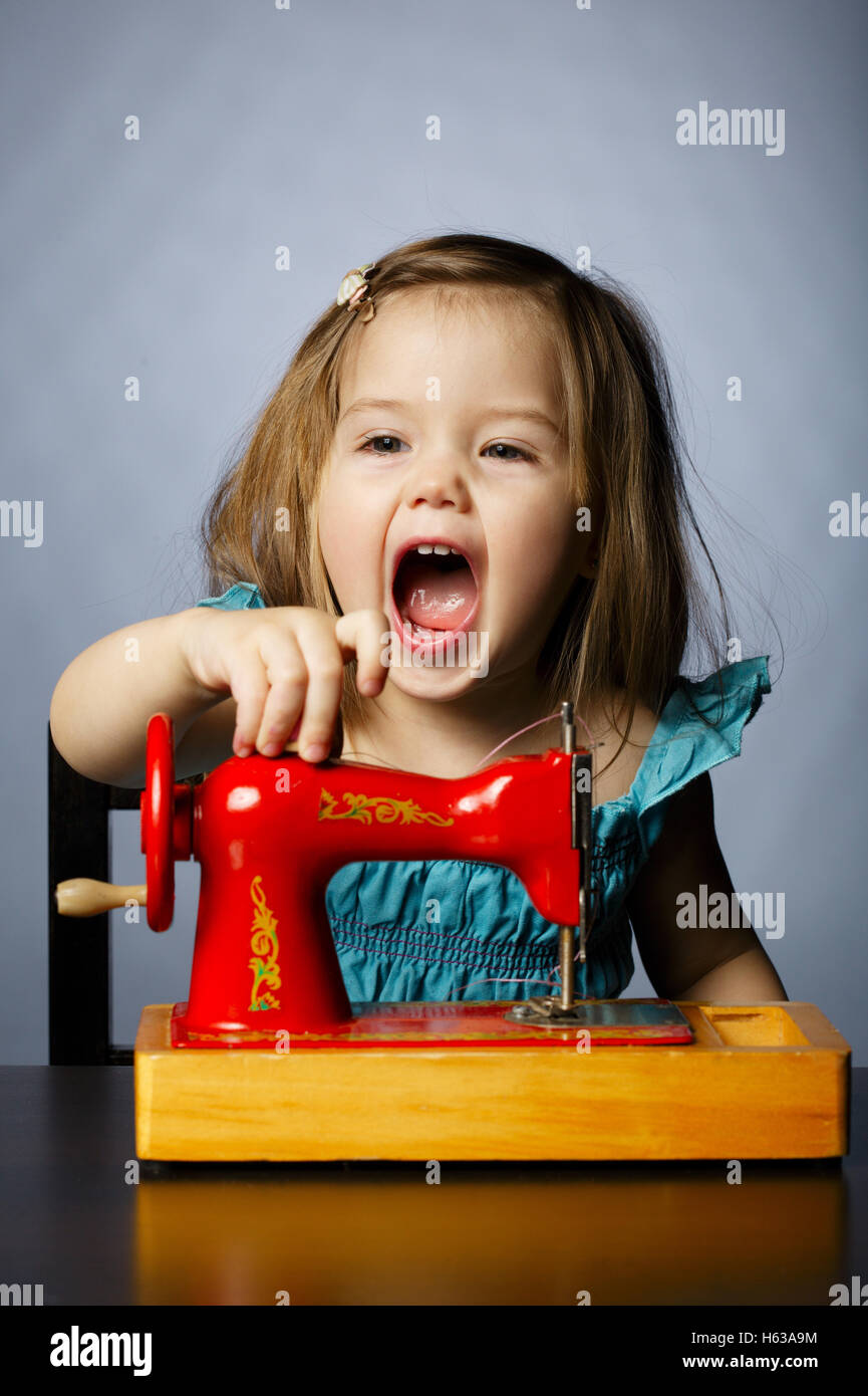 little girl is playing with sewing machine Stock Photo - Alamy