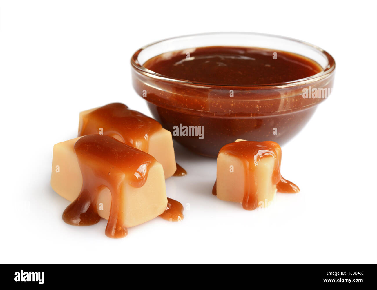Caramel candies and liquid caramel in glass bowl isolated on white ...