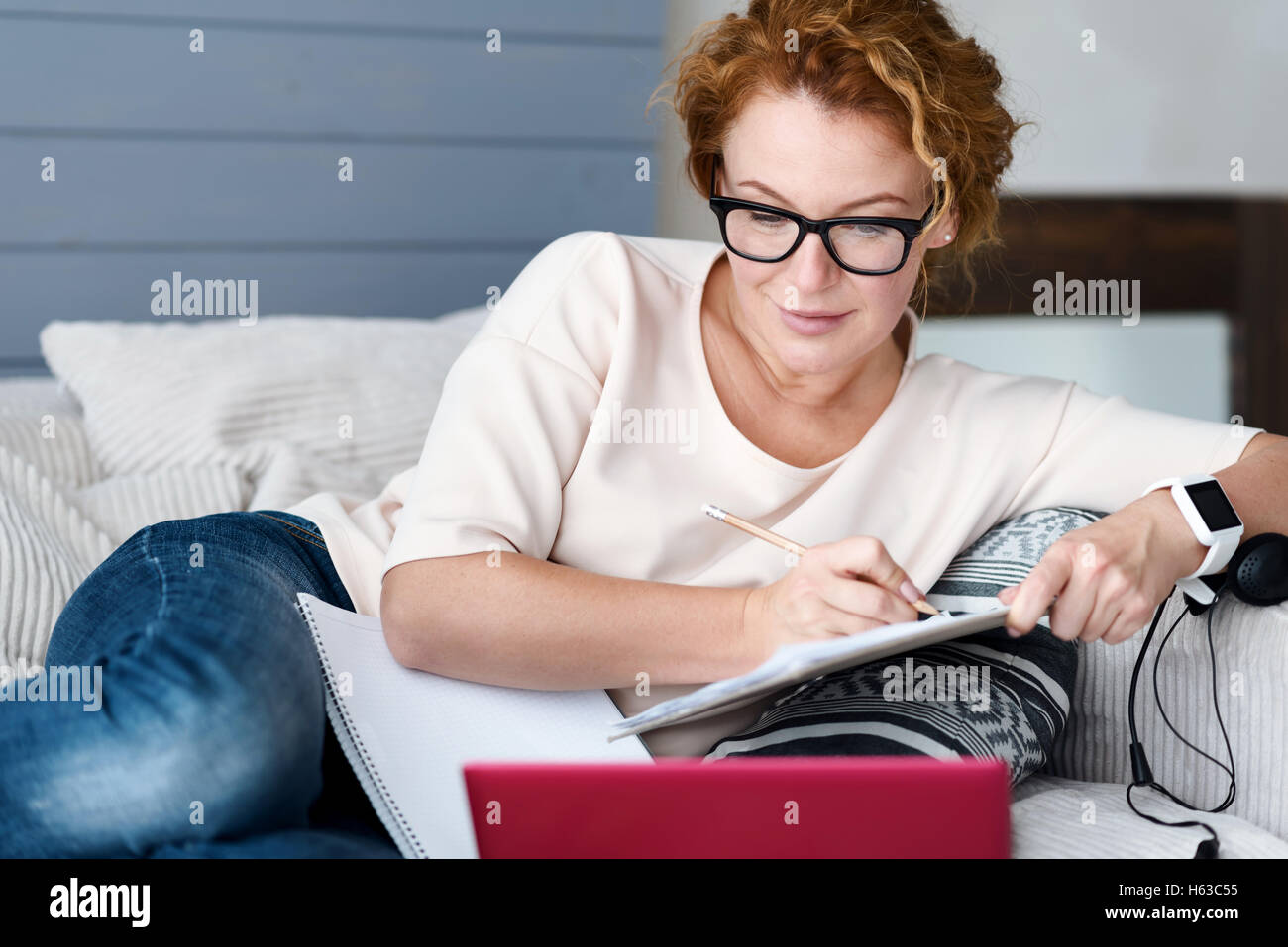 Woman on couch with laptop making notes Stock Photo - Alamy