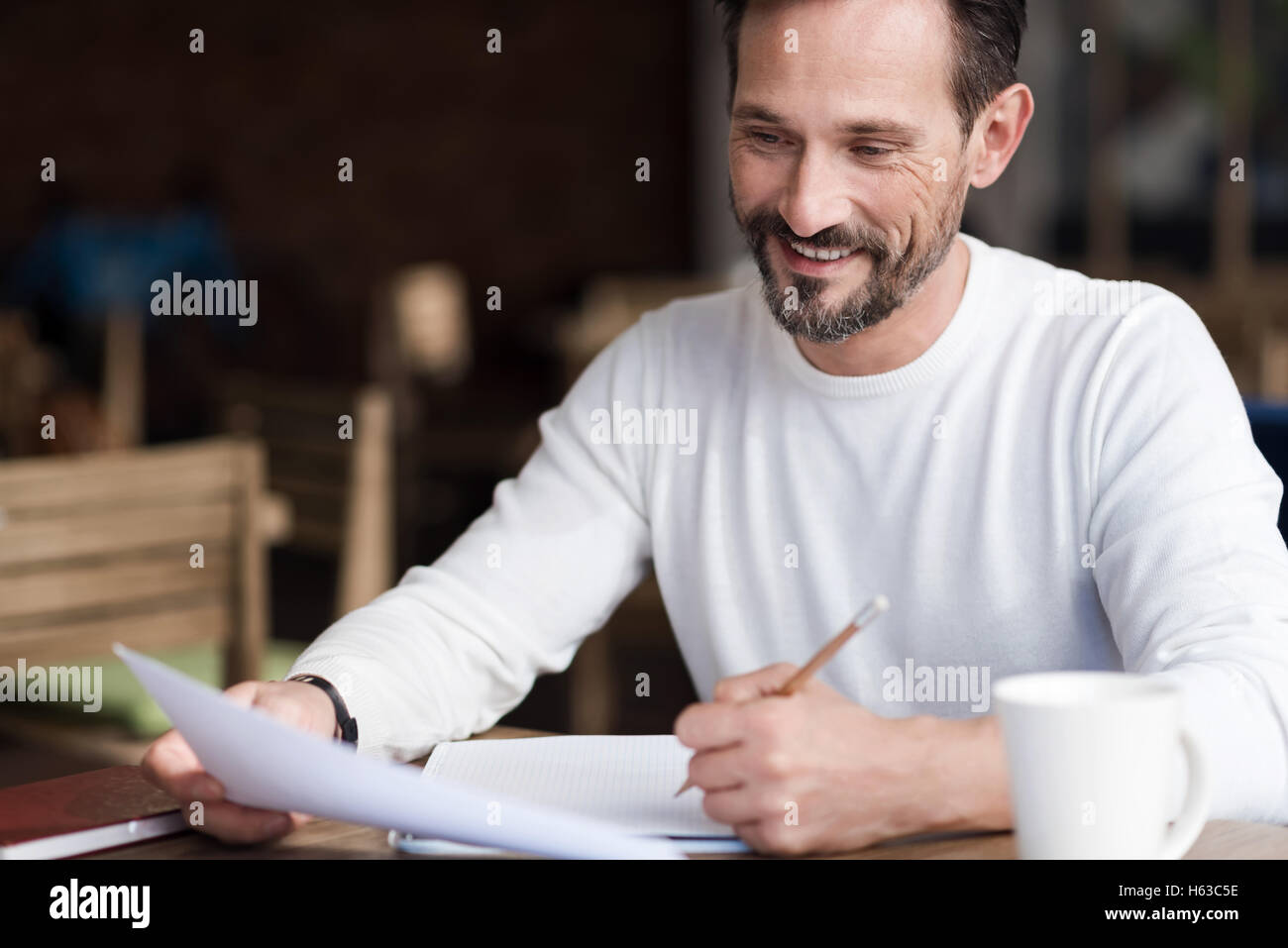 Bearded man taking notes in cafe Stock Photo - Alamy