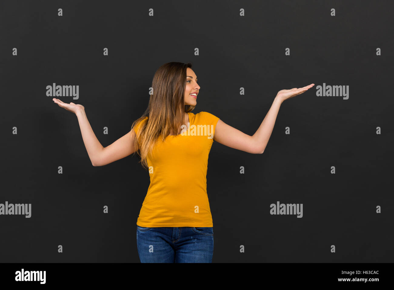 Beautiful woman with arms open in front of a black wall Stock Photo - Alamy