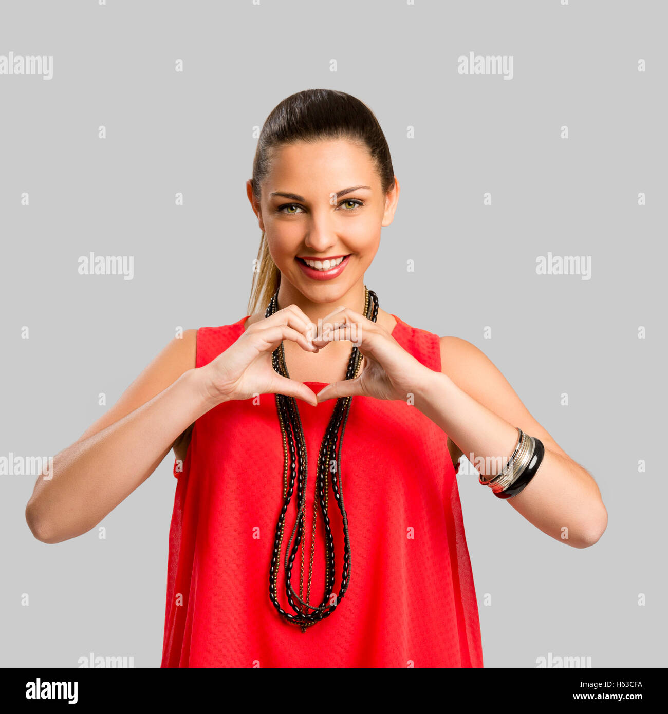 Portrait of a beautiful woman making the heart shape with her hands ...